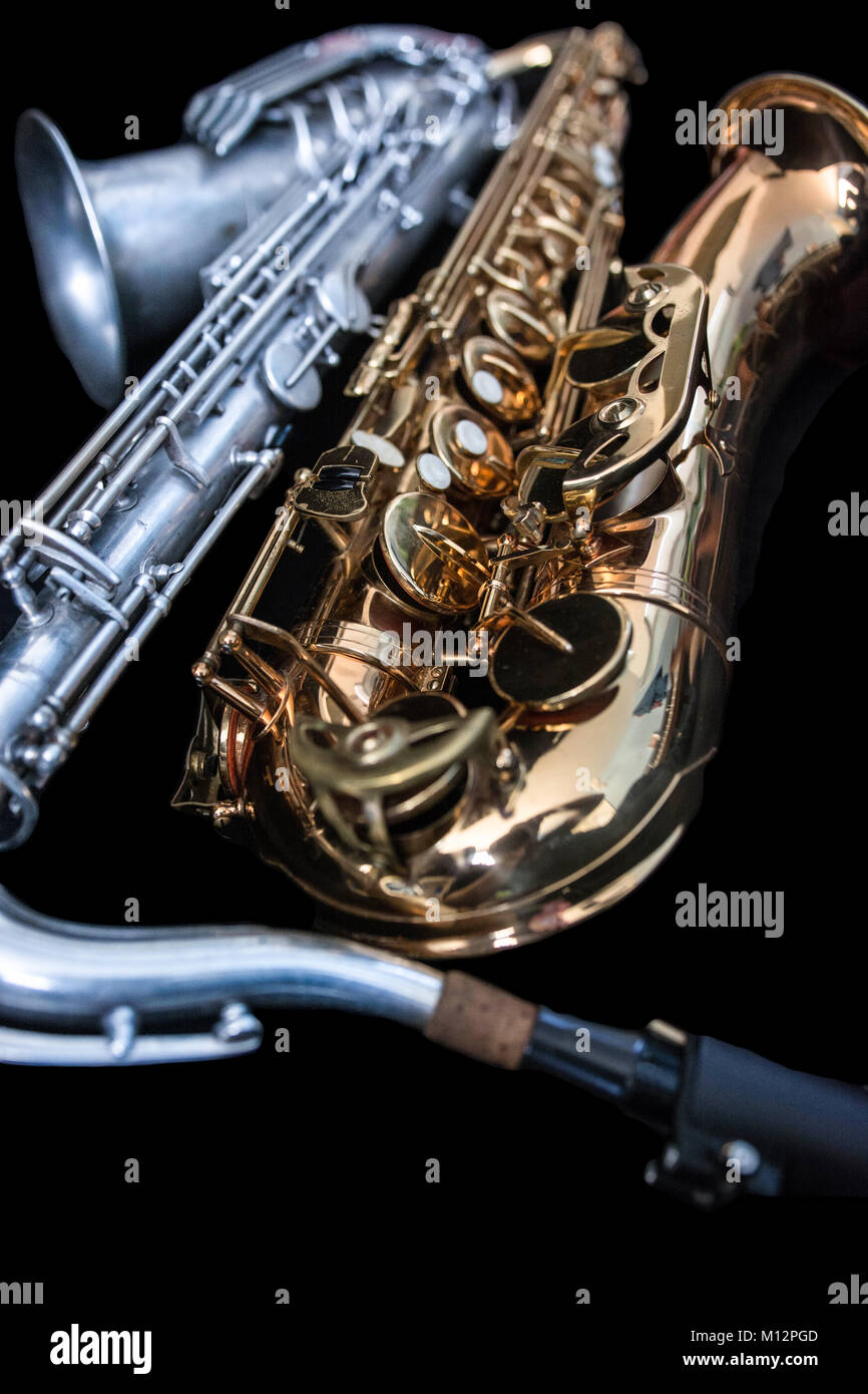 Close up of two saxophones lying down isolated in black Stock Photo - Alamy