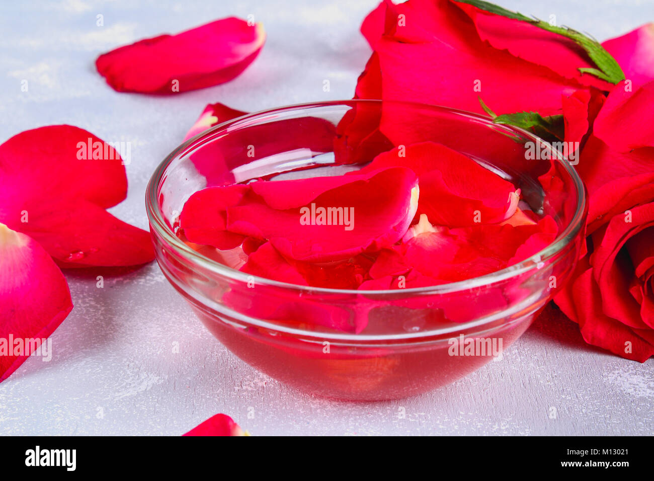Pink water from rose petals on a gray table. Spa Stock Photo - Alamy