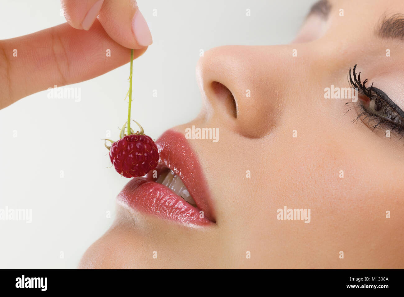 young beautiful woman eating raspberries Stock Photo - Alamy