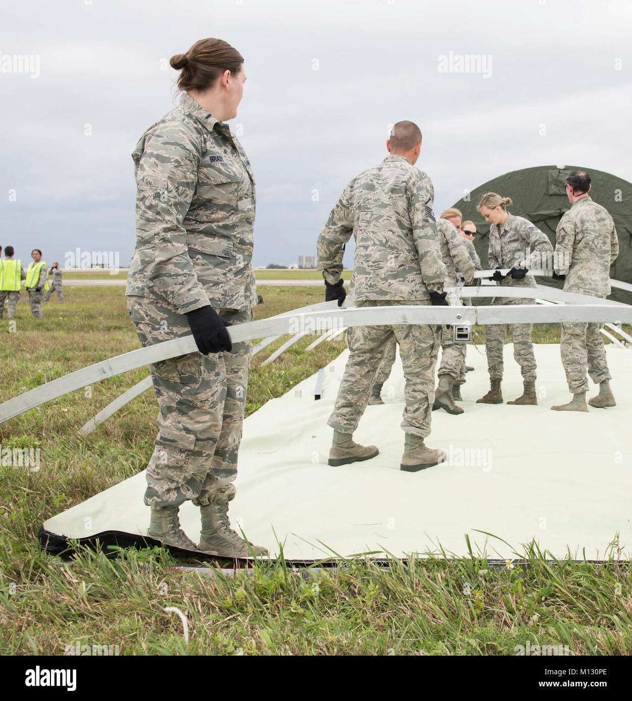 Members of the 18th Medical Group assemble a tent near the flightline ...