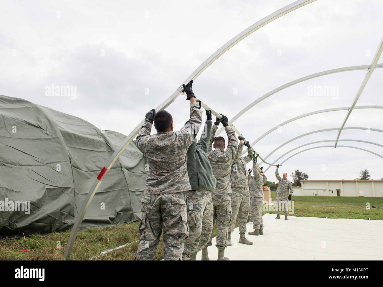 Members of the 18th Medical Group assemble a tent near the flightline ...