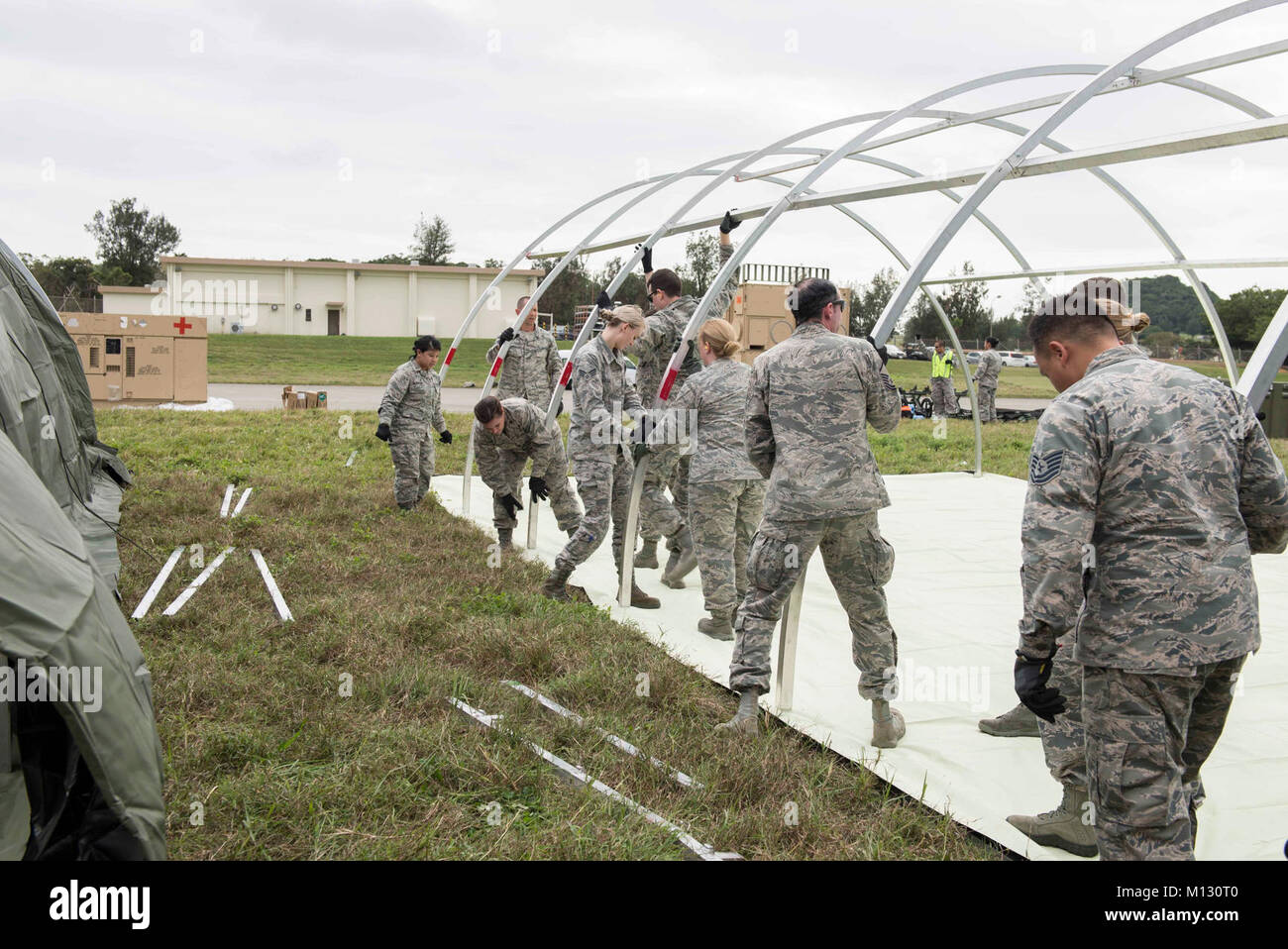 Members of the 18th Medical Group assemble a tent near the flightline ...