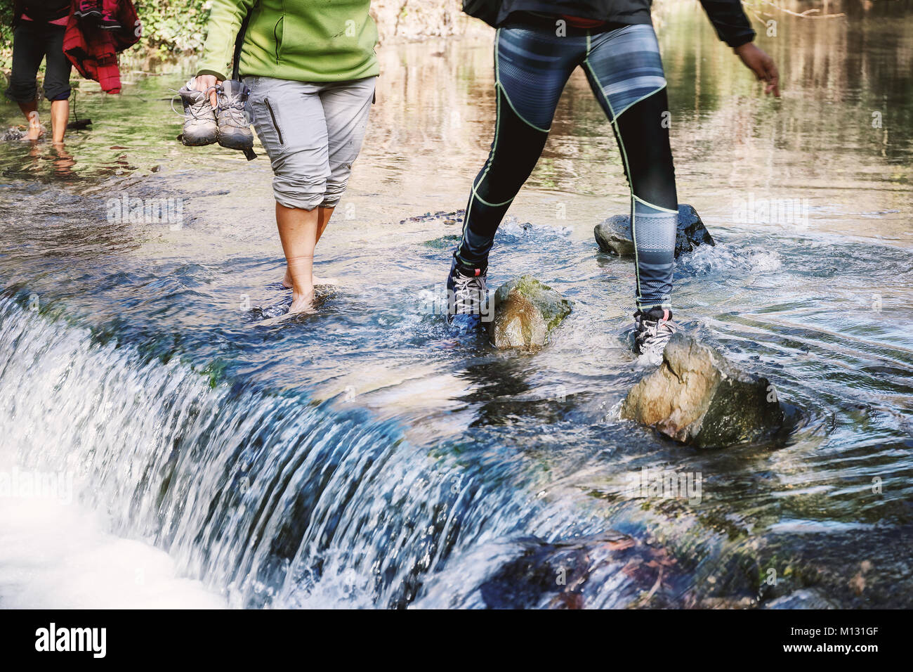 Hiking, three people wade the river on foot, at the point where the ...
