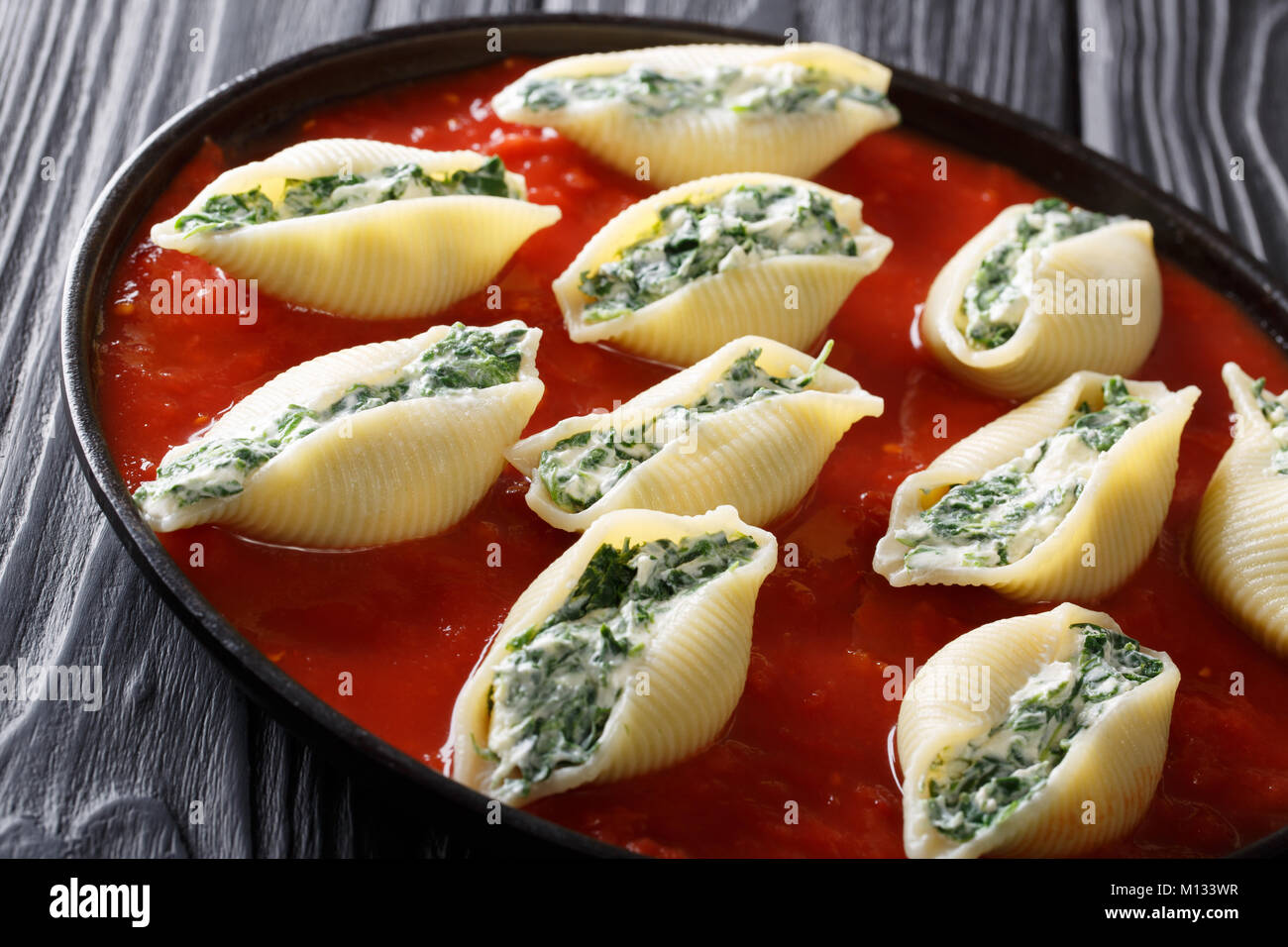 Shell pasta with spinach and cream cheese with tomato sauce closeup on ...
