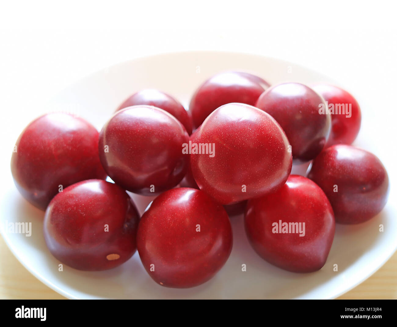 Closed up Red Color Ripe Gulf Ruby Plum Fruits Piled up on White Plate ...