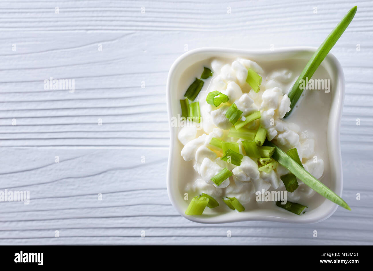 Homemade cottage cheese with green onions on white wooden table. Top ...