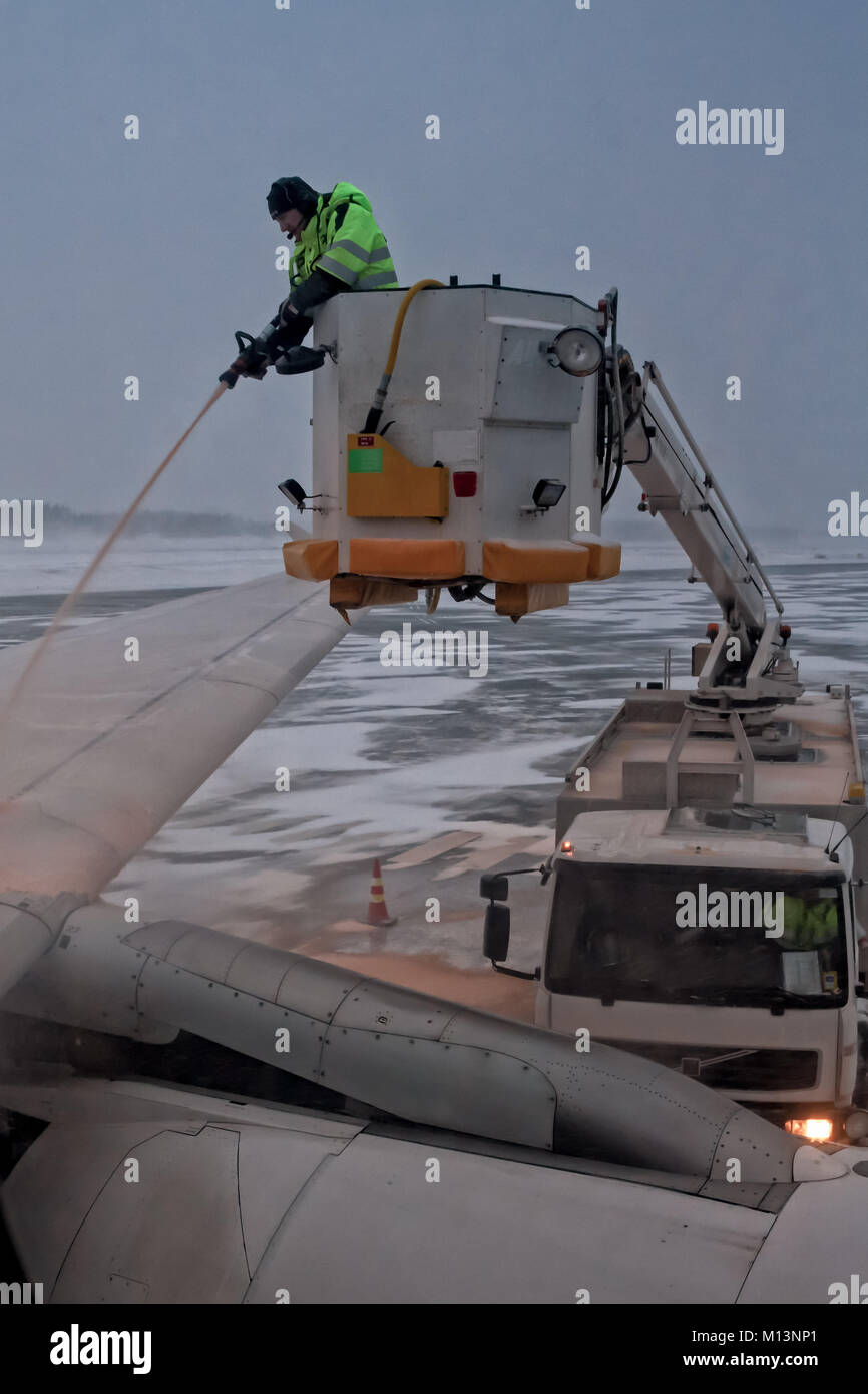 The airport staff de-ice the wings of an airplane taking off at the ...