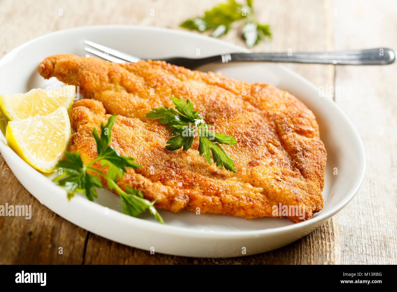 Breaded fried meat with a fresh lemon wedge Stock Photo - Alamy