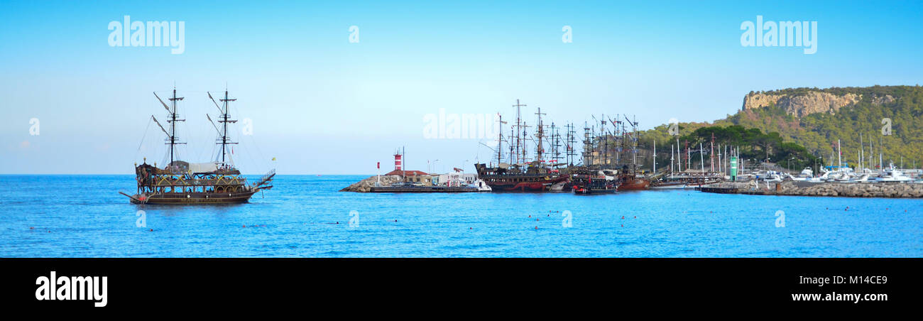 Yacht in pirate style enters marina bay harbor with other moored yachts ...
