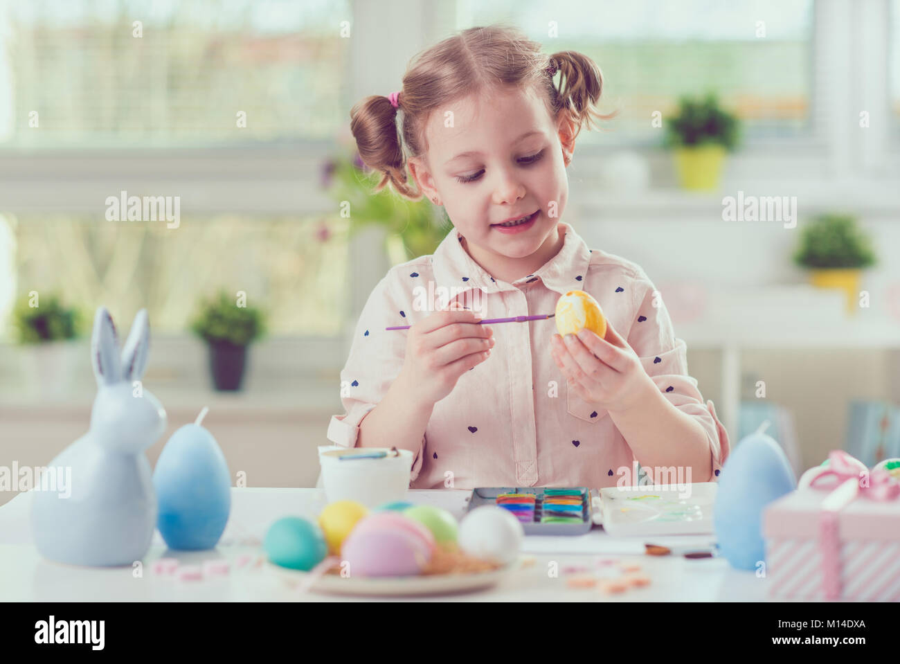 Happy pretty child girl having fun during painting eggs for easter in ...