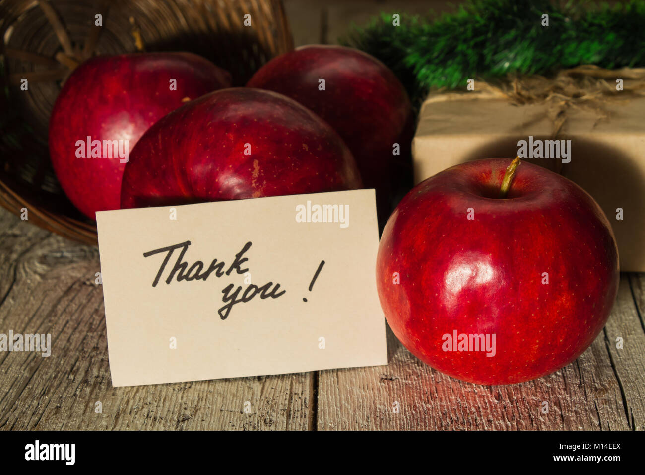 red apples with a gift and a postcard with text Thank You on a wooden ...