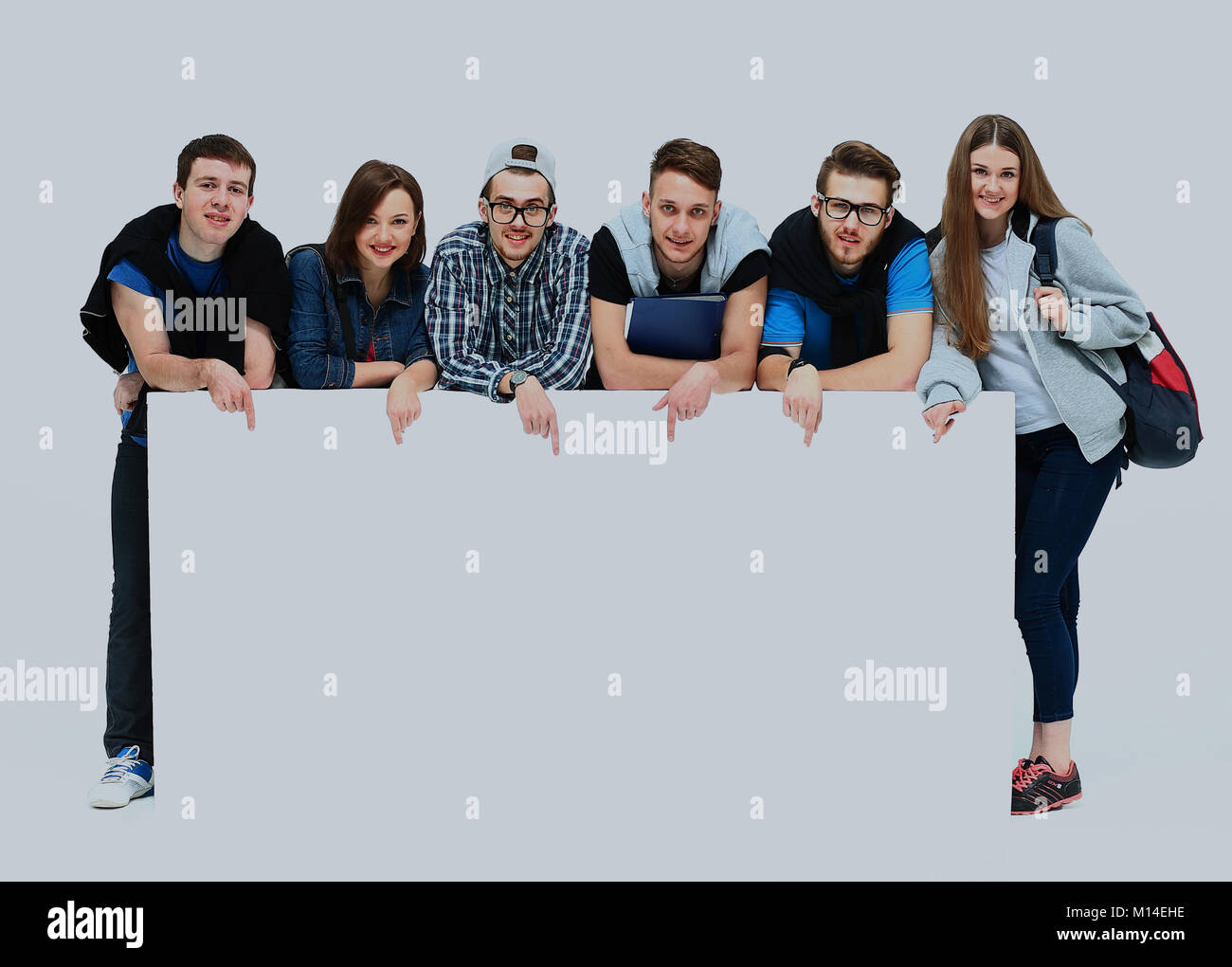 Full length portrait of confident college students displaying blank ...