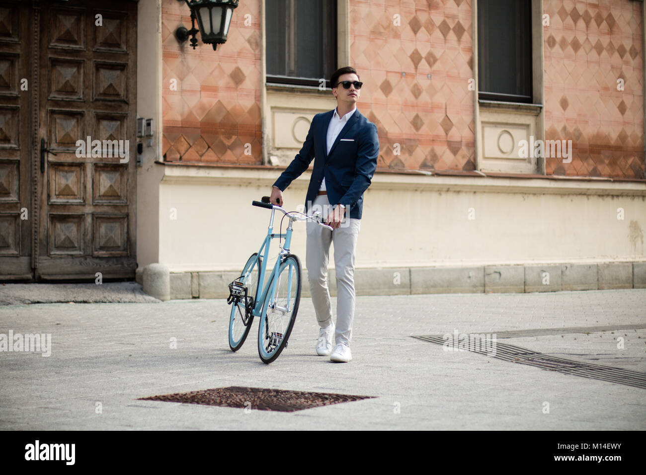 Elegant young man with blue bicycle outdoors on the street Stock Photo ...
