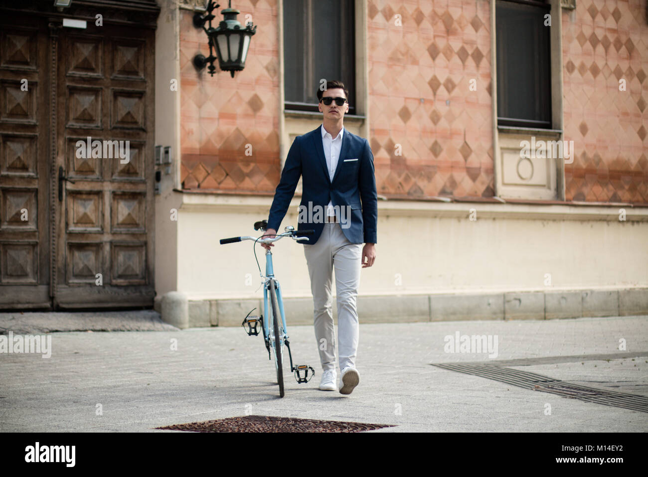 Elegant young man with blue bicycle outdoors on the street Stock Photo ...