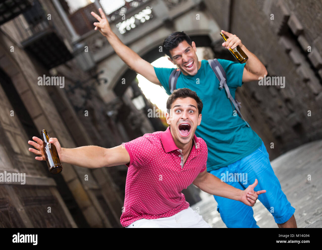 two smiling active male fans who are walking with beer in Barcelona ...