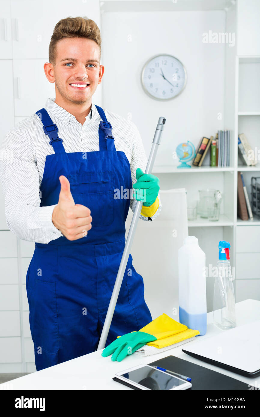 Smiling friendly male professional janitor dusting in modern office ...