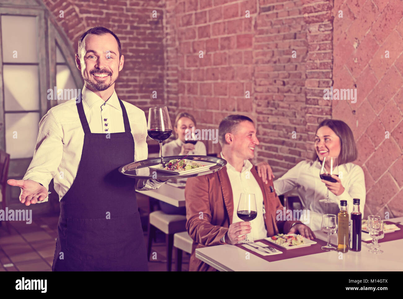 Young man waiter demonstrating country restaurant to visitors Stock ...