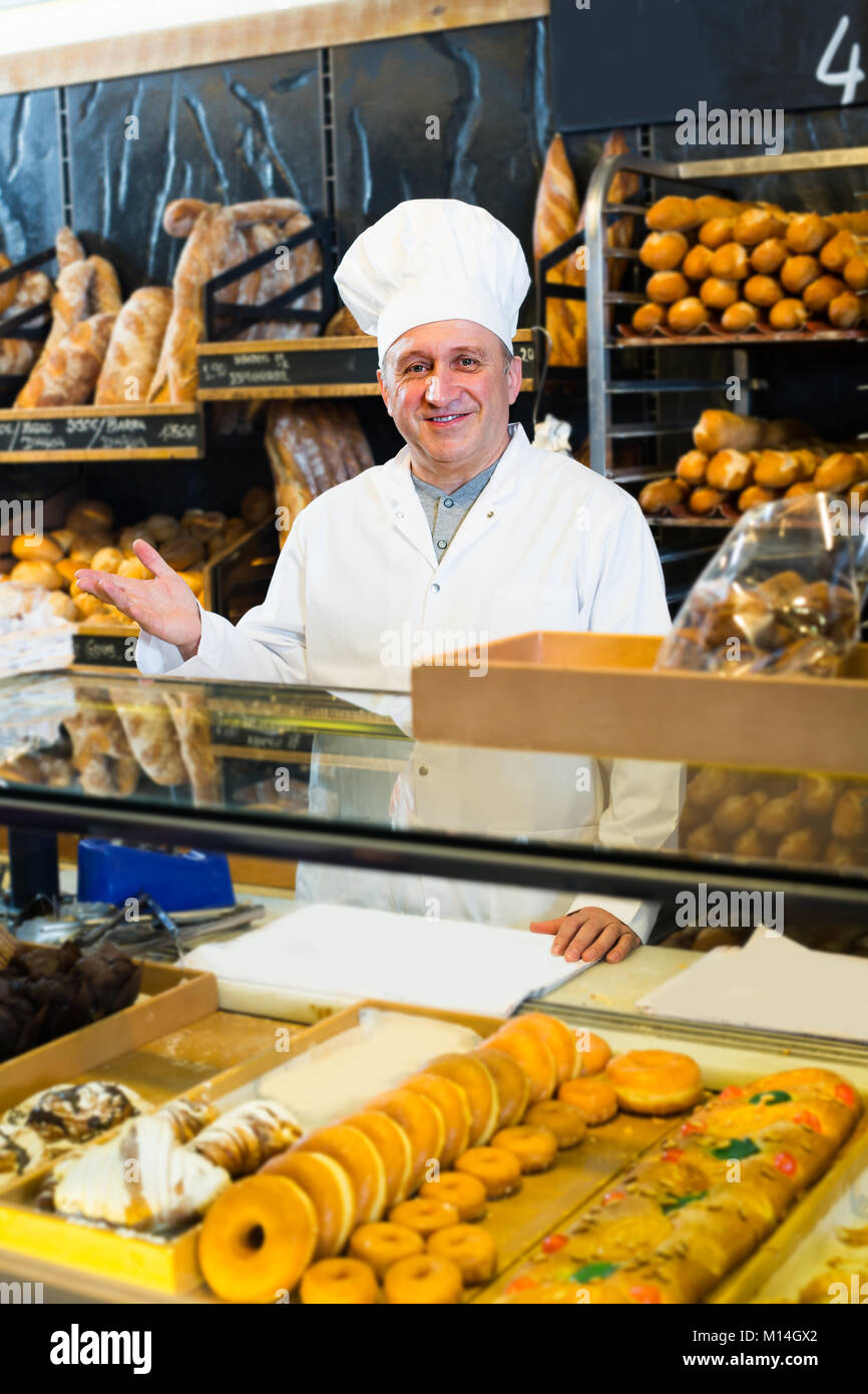 Mature male staff posing with fresh pastry in sweet-shop Stock Photo ...