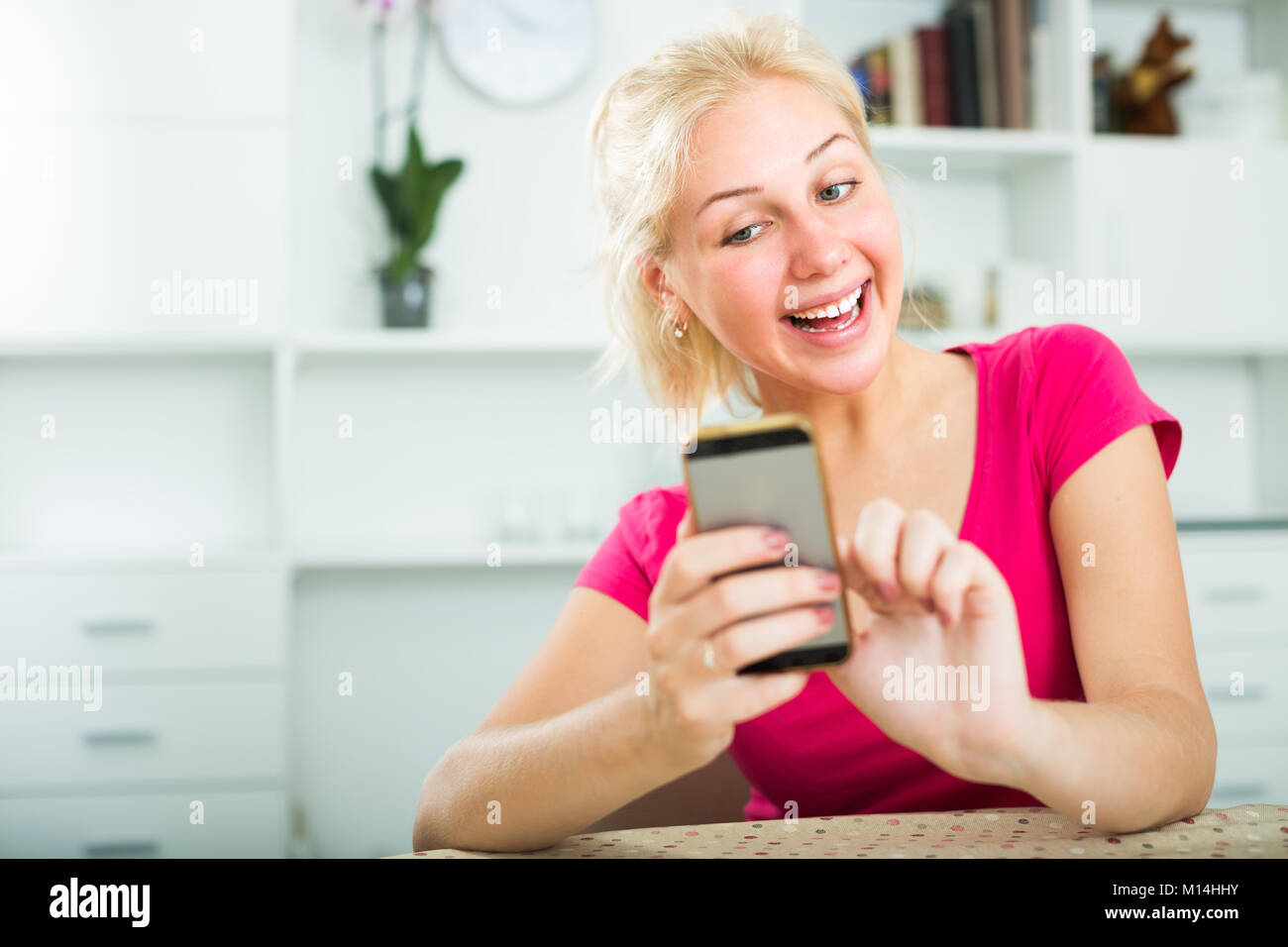 joyful smiling young woman looking on mobile phone screen sitting at ...