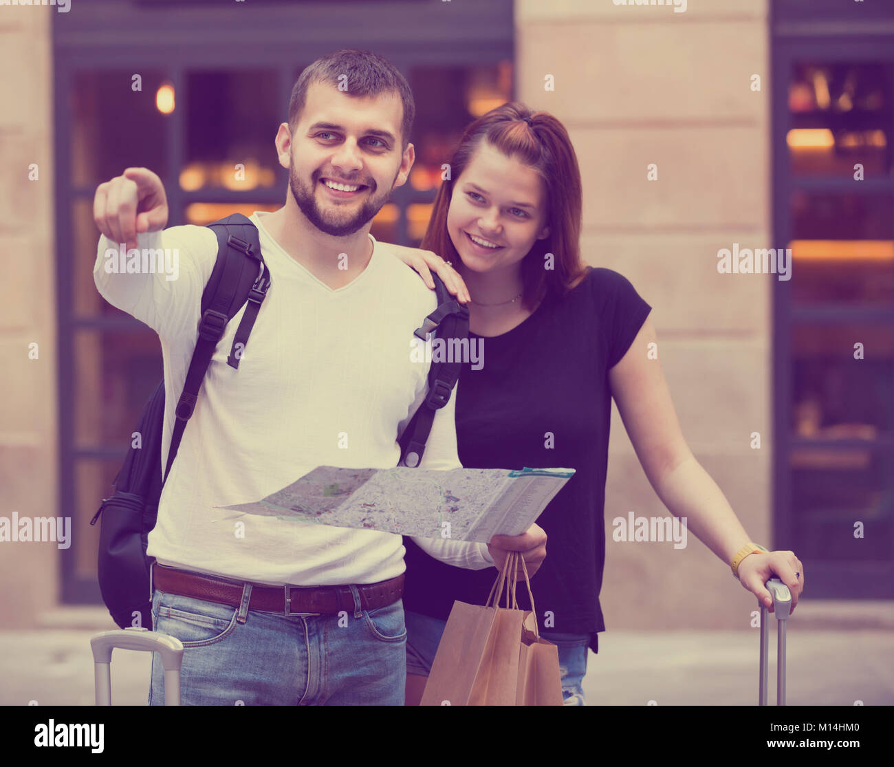 Portrait of smiling tourists with map walking with baggage on vacation ...