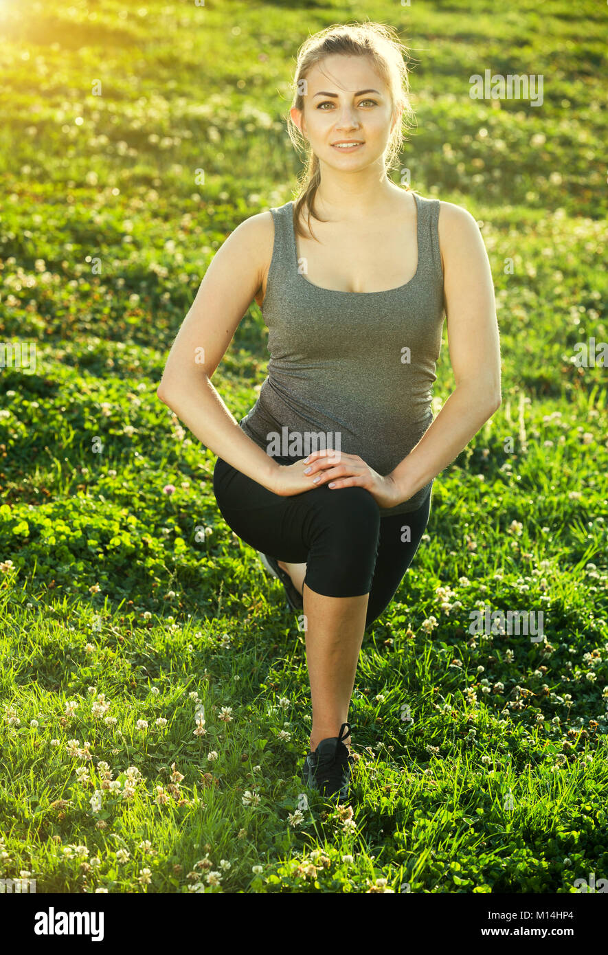 happy european woman in sportwear doing exercises on mat in the garden ...