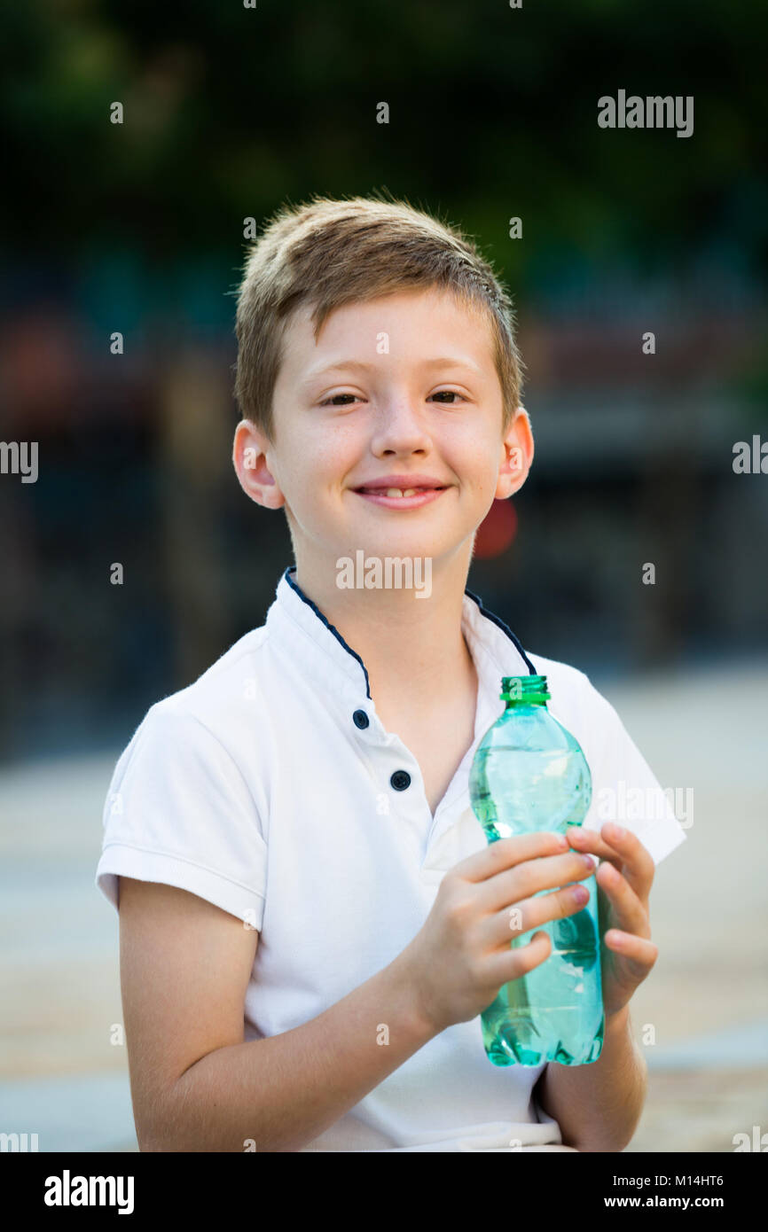 portrait of glad boy drinking water in park on summer day Stock Photo ...