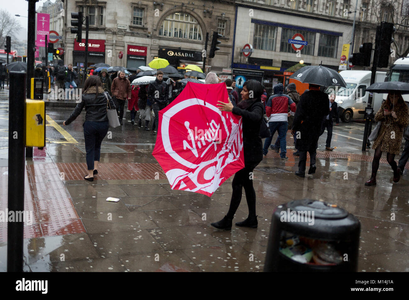 A lady carrying a Virgin Active brolly which has caught in the wind as ...