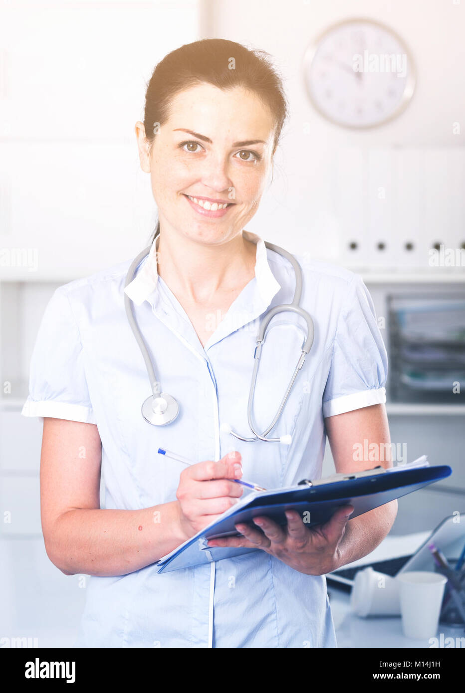 Smiling female doctor filling documents in medical center with ...