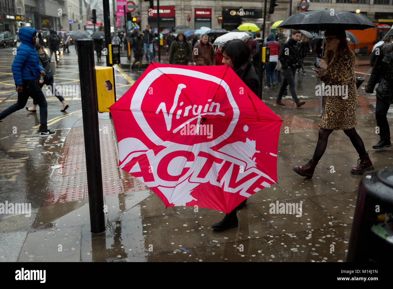 A lady carrying a Virgin Active brolly which has caught in the wind as ...