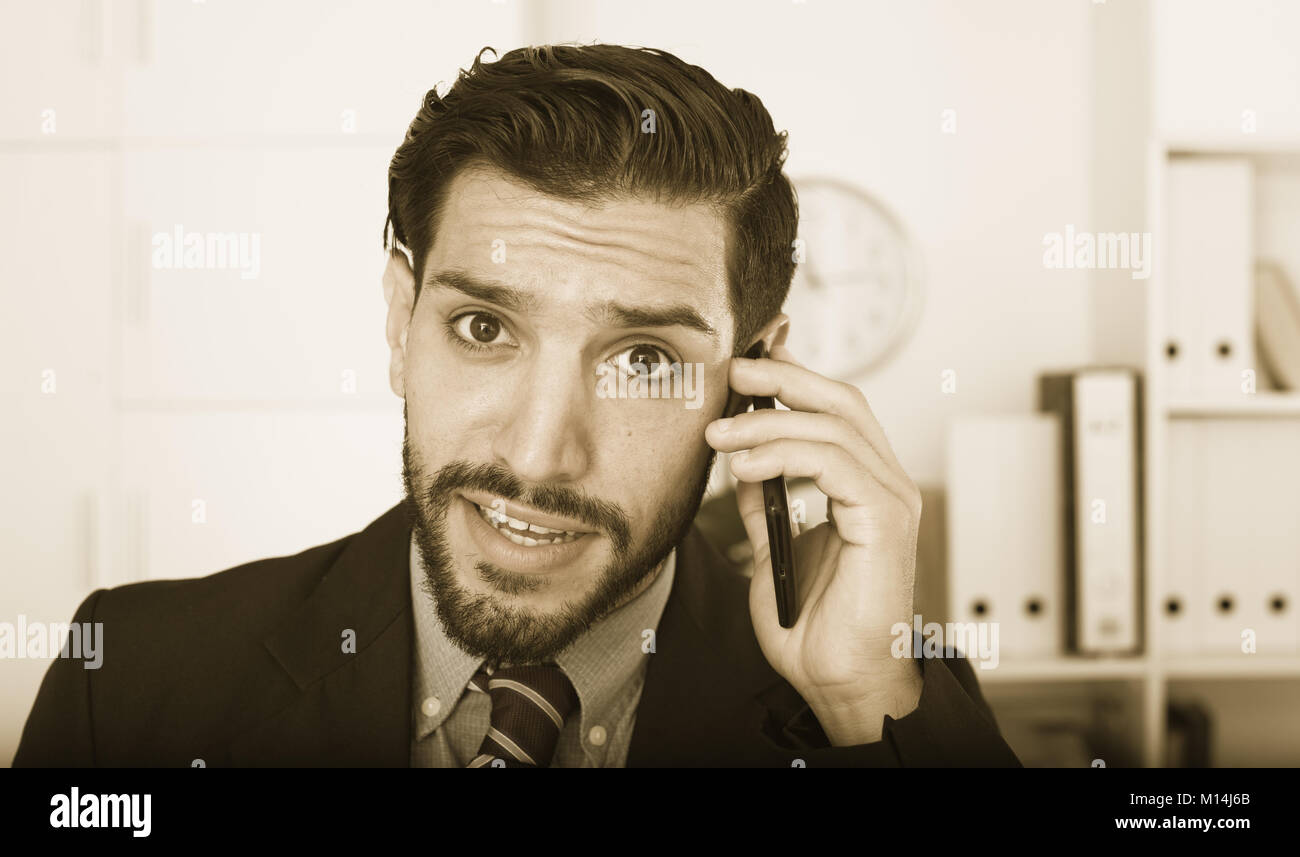 Surprised spanish businessman is talking phone with his partner in ...