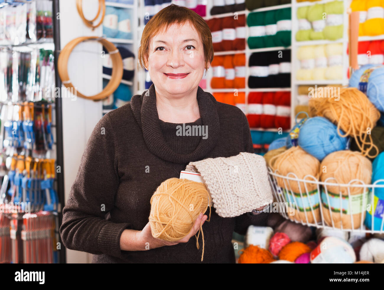 Positive woman picking yarn in color to knitted pattern in needlework ...