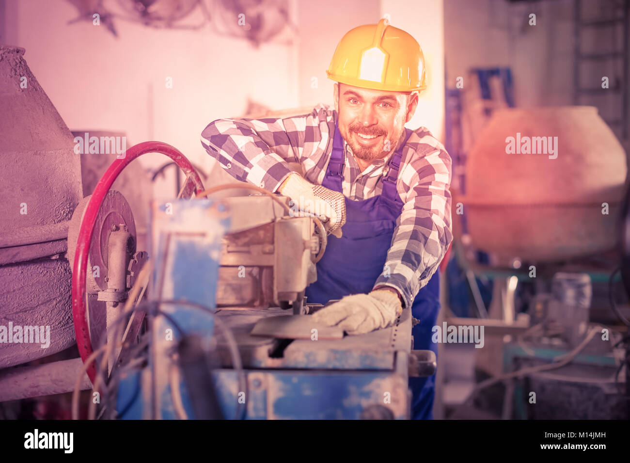Smiling working man practicing his skills with disk saw machine at the ...
