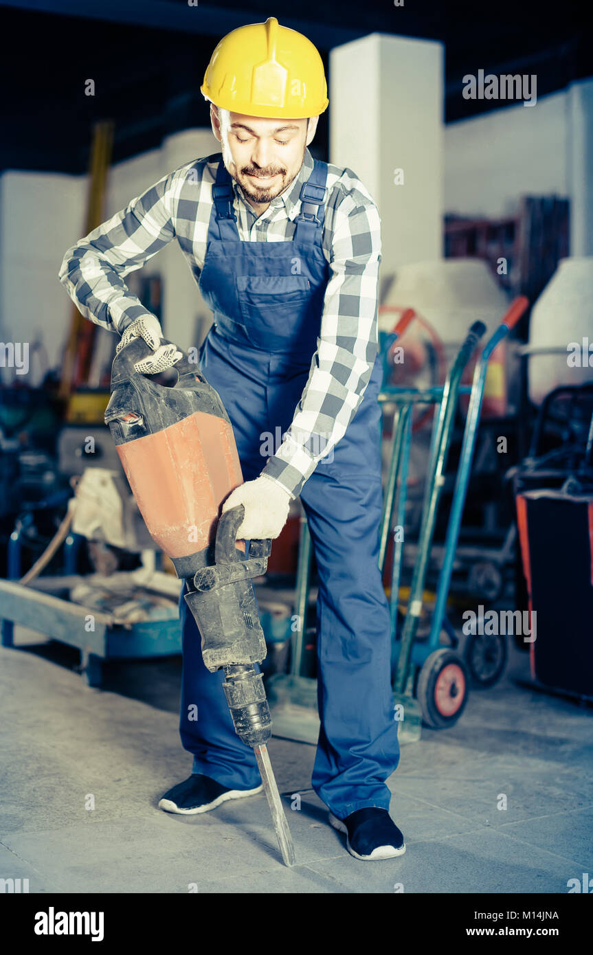 positive working man practicing his skills with pneumatic drill at ...