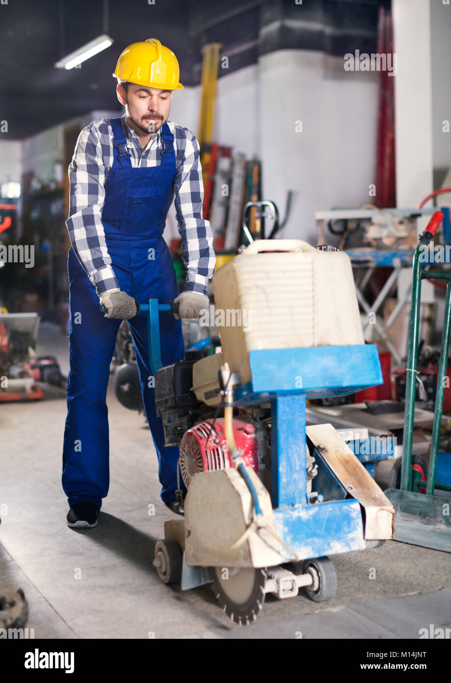Smiling working man practicing his skills with edger at workshop Stock ...