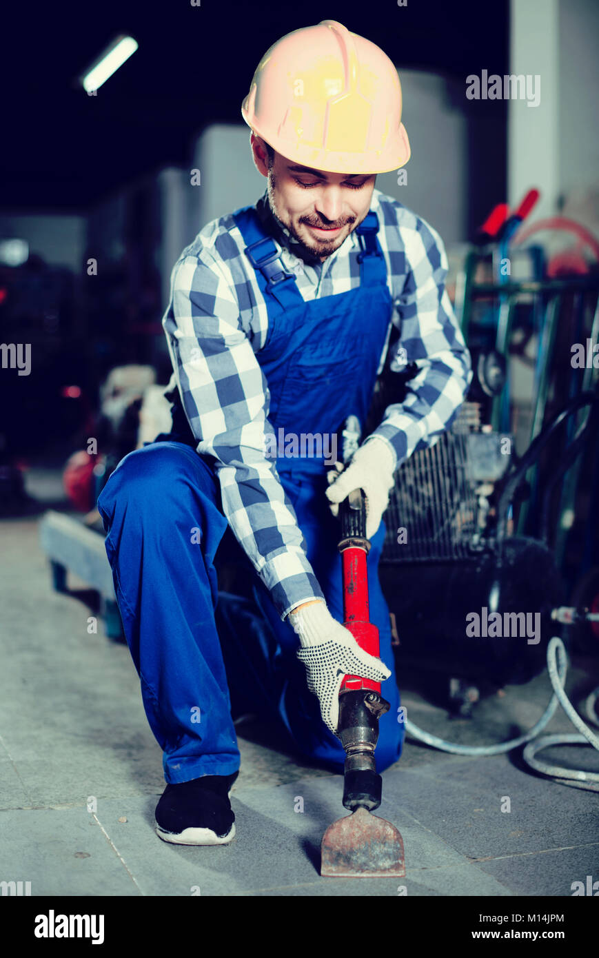 Positive adult male worker starting to work with demolition hammer at ...
