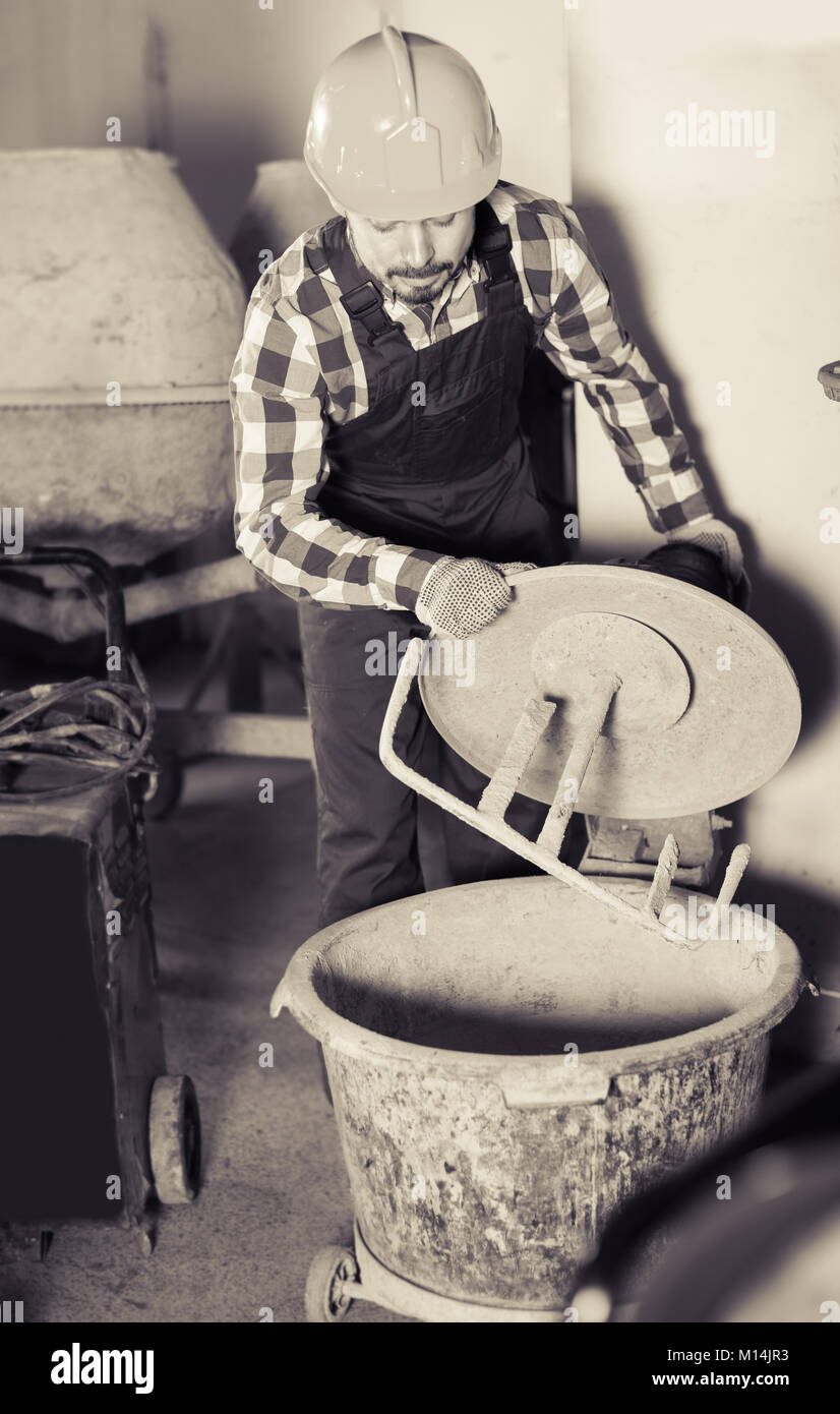Young smiling male using concrete mixer for construction work at ...