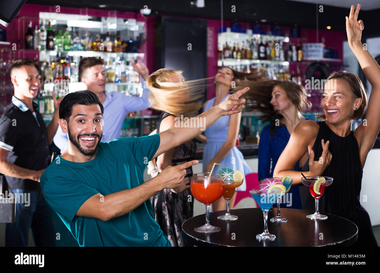 Cheerful woman with man are dancing and drinking cocktail on the party ...
