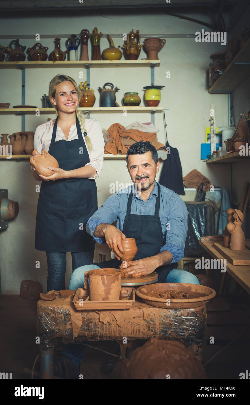 two smiling potters making ceramic vessels on pottery wheel in ceramics ...