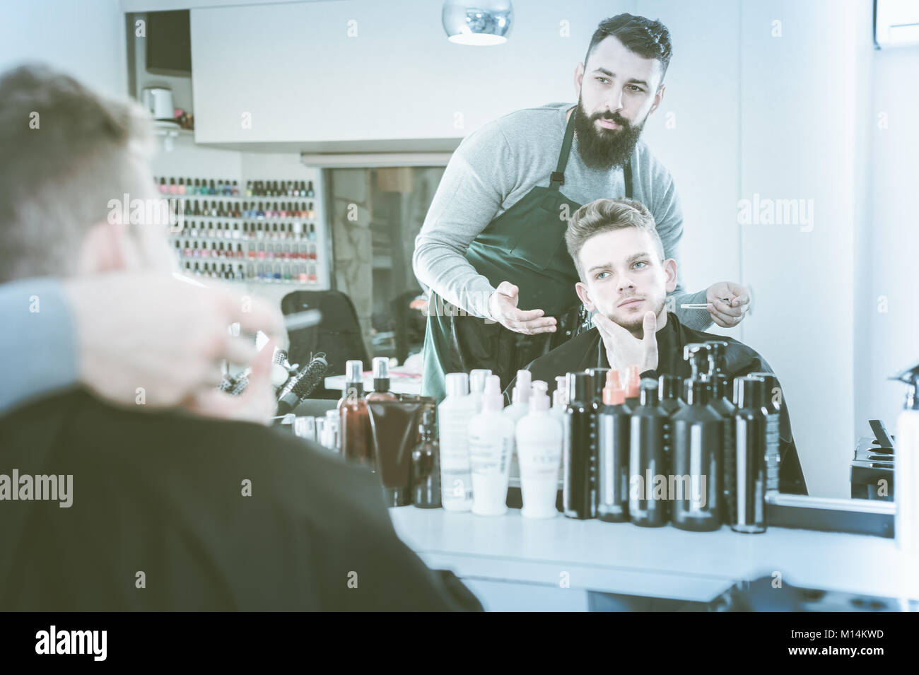 thoughtful guy stylist creating new haircut for man client at ...