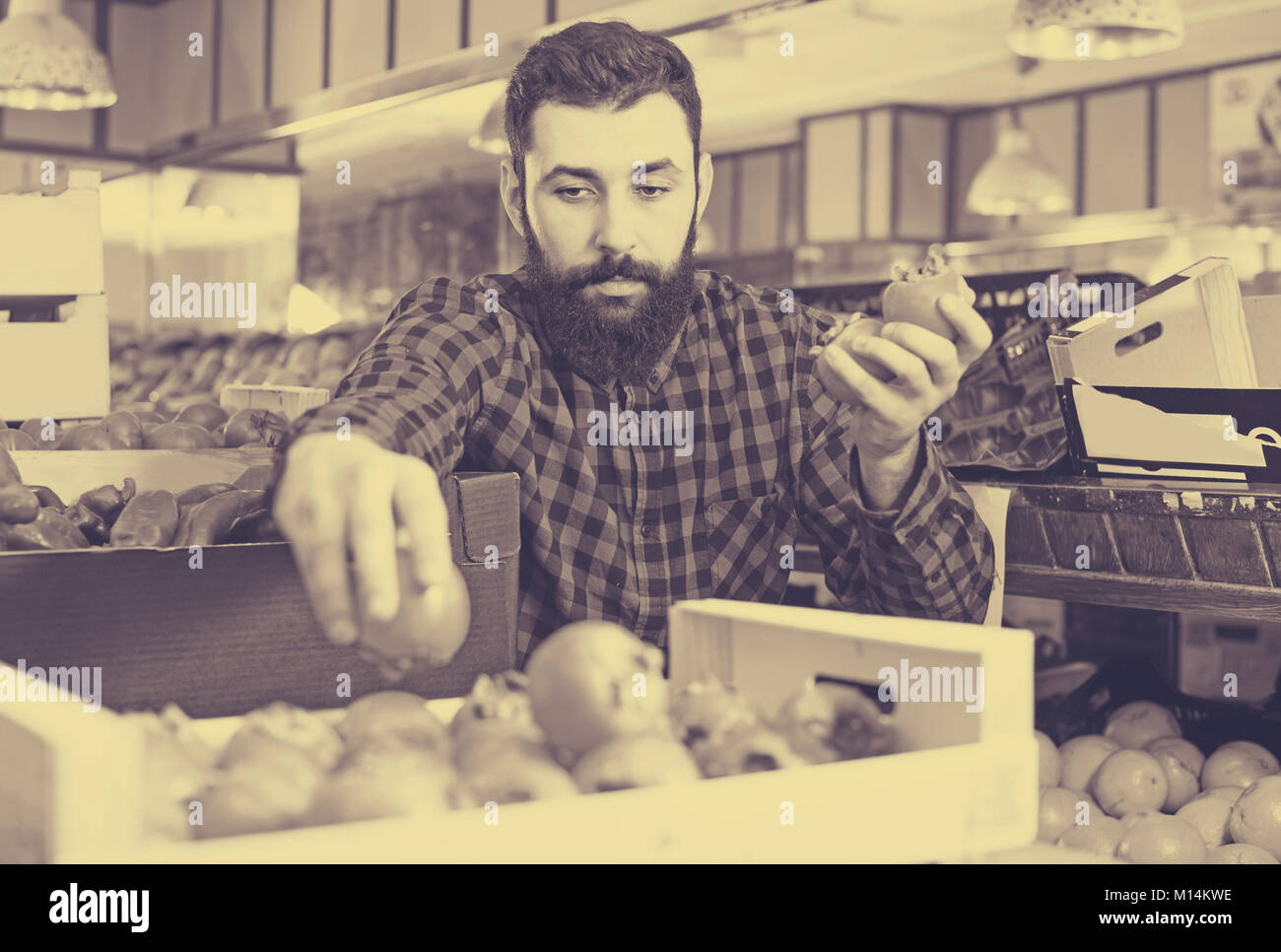 Male shop assistant demonstrating persimmons in grocery shop Stock ...