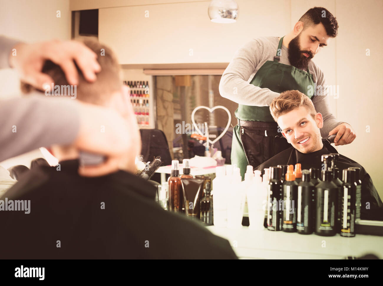 Man hairdresser doing new haircut for happy young guy client at hair ...