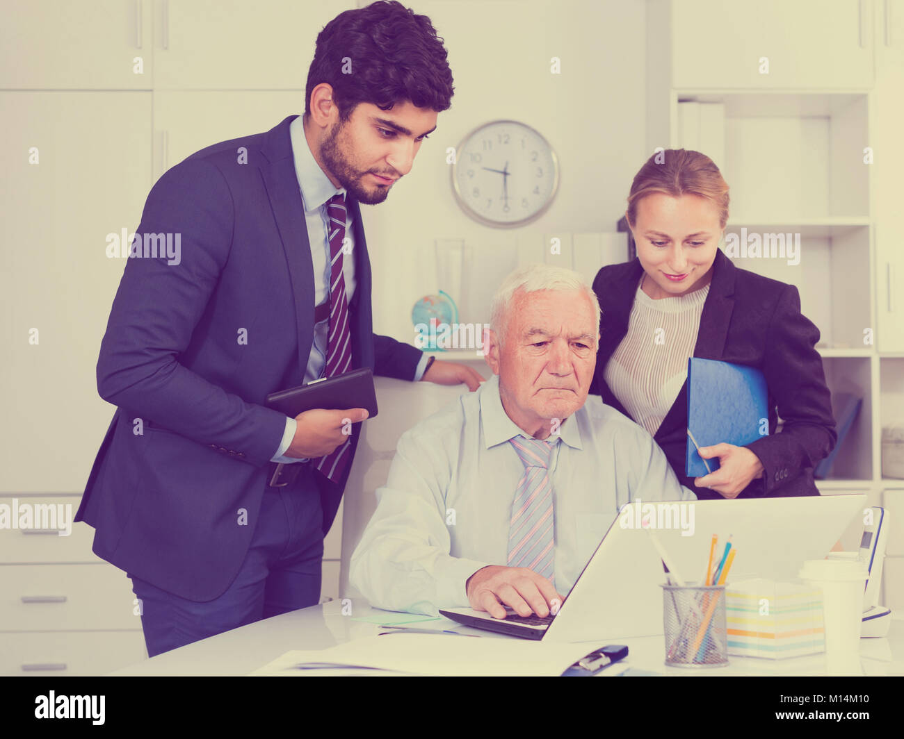 Employees are demonstrating reports on laptop to mature boss in the ...