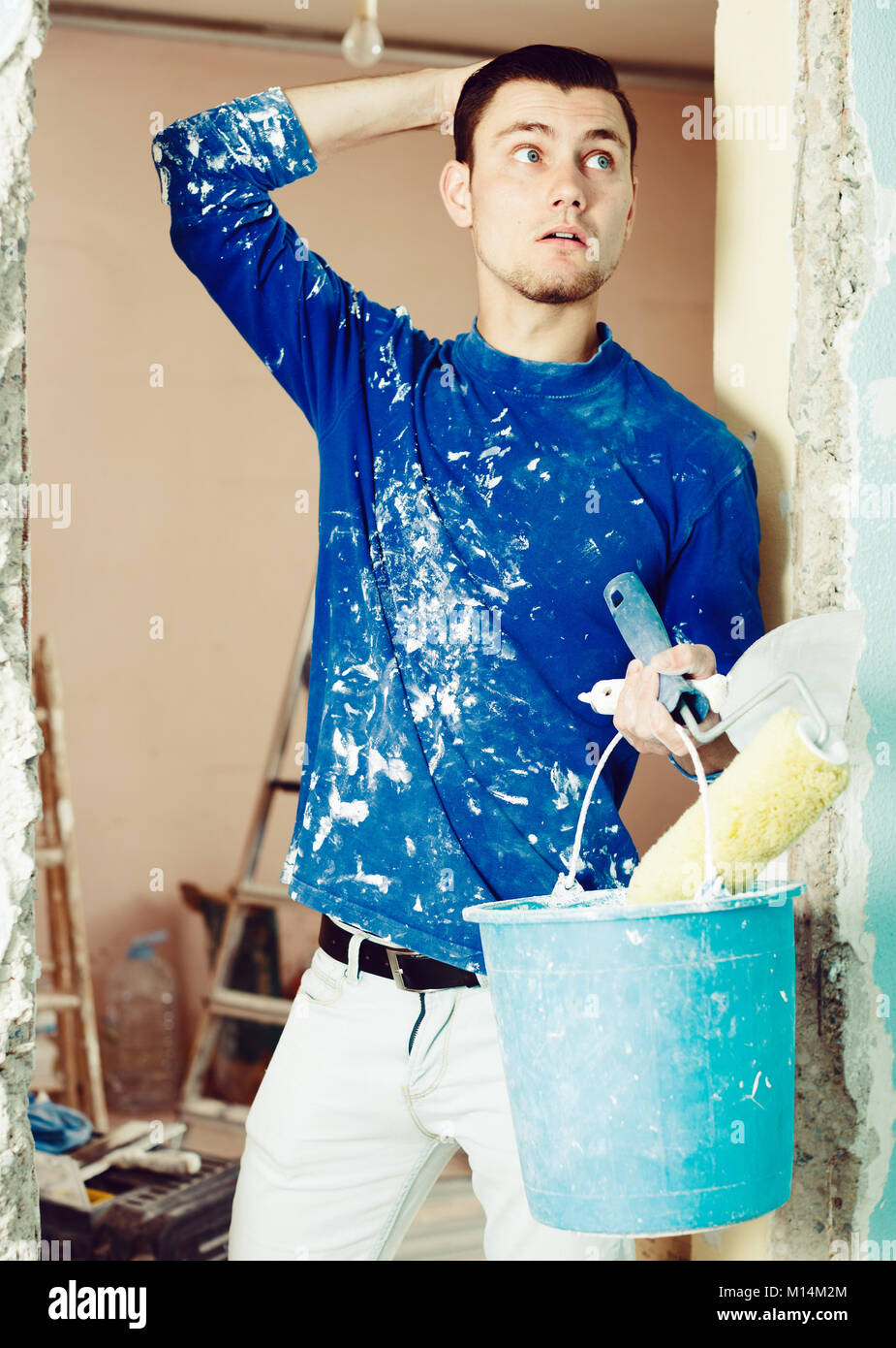 Puzzled young builder handyman examining room and planning renovation ...