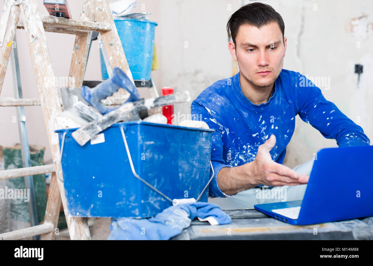 Serious builder handyman checking plan of house renovation on laptop ...