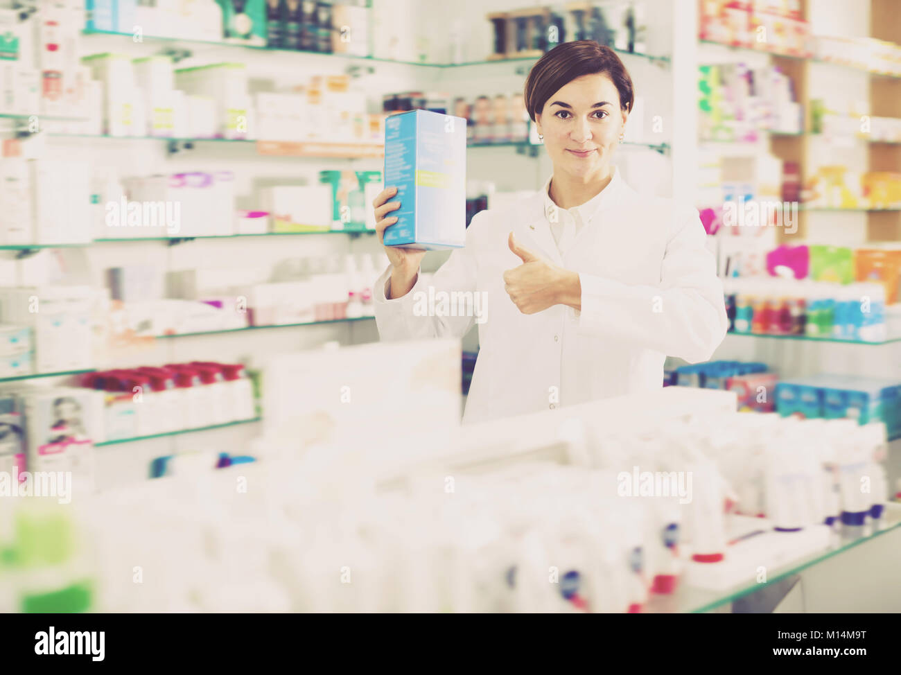 Ordinary female pharmacist offering products of body care in pharmacy ...