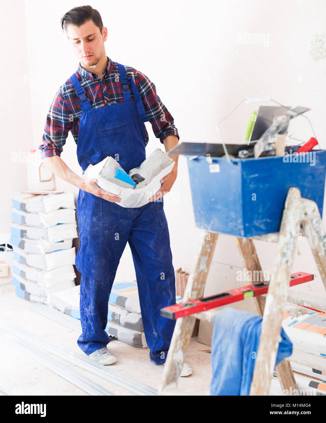 Young handyman going kneading putty during house renovation Stock Photo ...