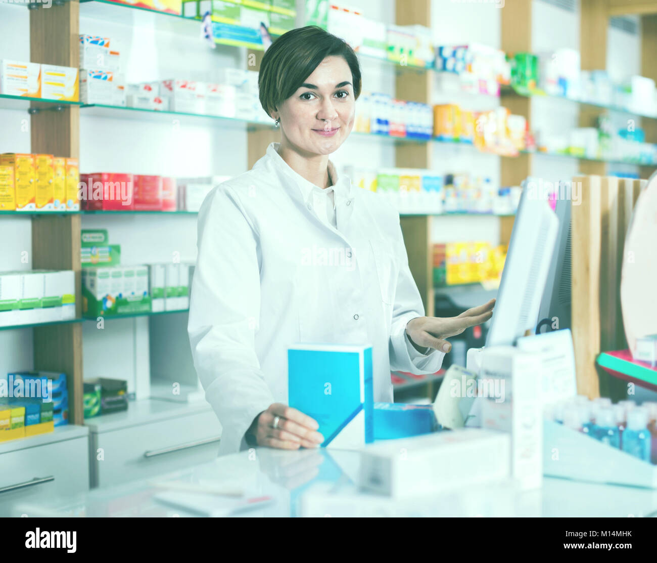 Happy cheerful female pharmacist offering help in choosing at counter ...
