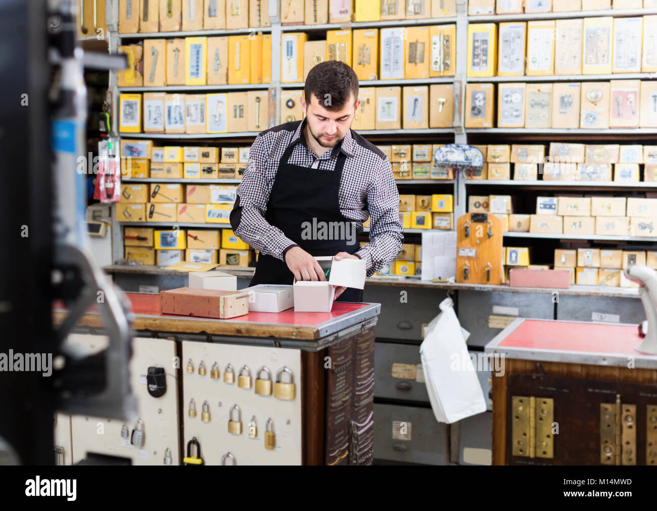 Man seller sorting boxes with door details in houseware shop Stock ...