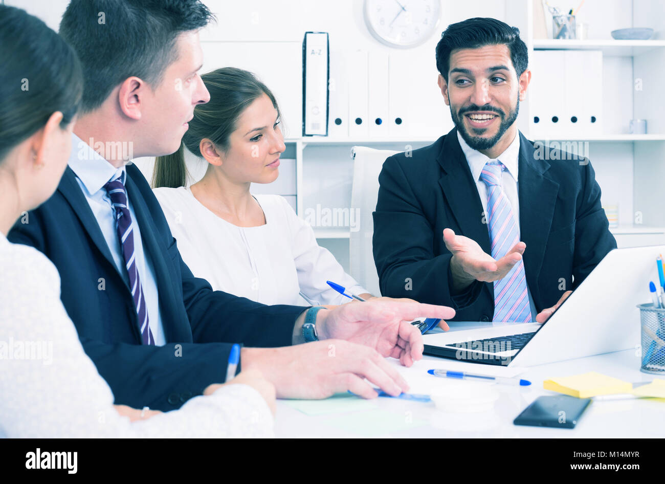 Smiling businessman explaining business strategy to partners in office ...