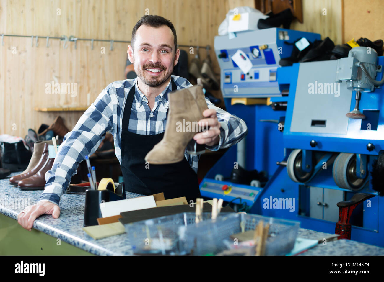 Male worker showing fixed shoes in shoe repair workshop Stock Photo - Alamy